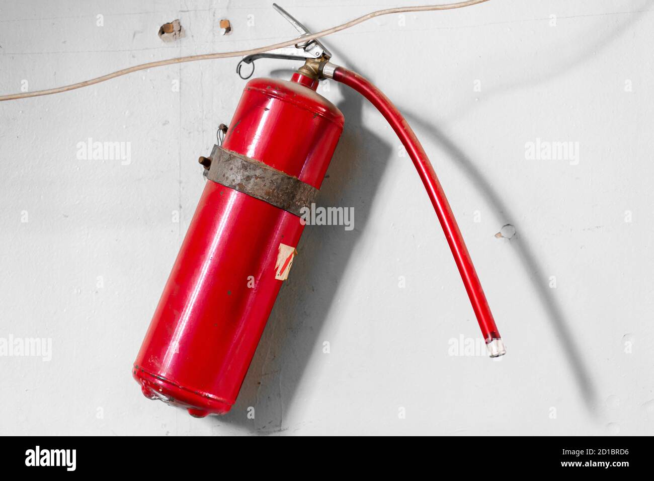A red balloon fire extinguisher hangs on a white wall. Fire safety in ...