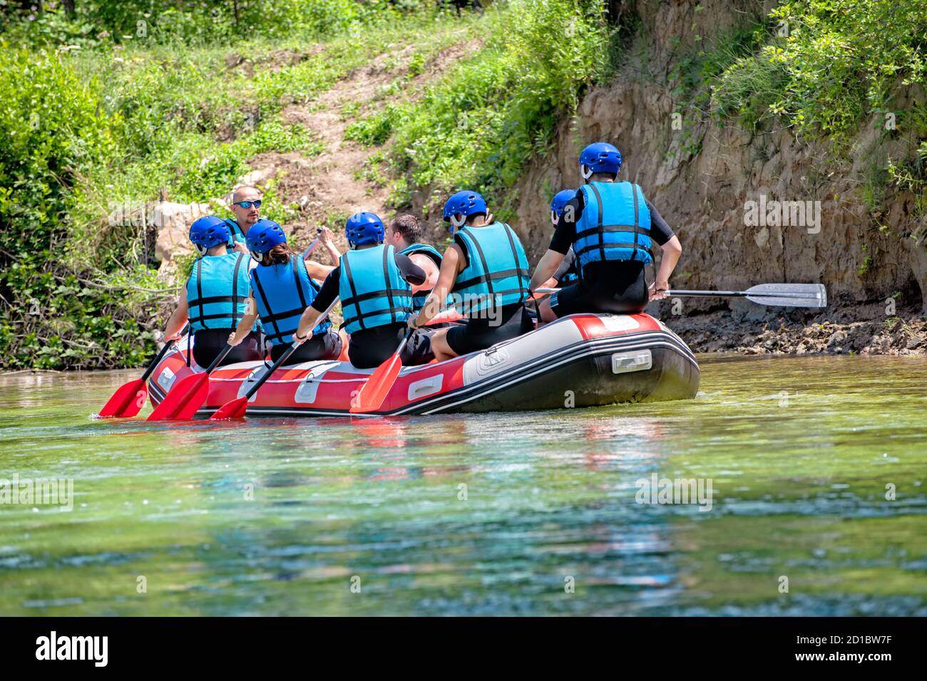 Rafting team goes down the river on the beautiful sunny day. Back view ...