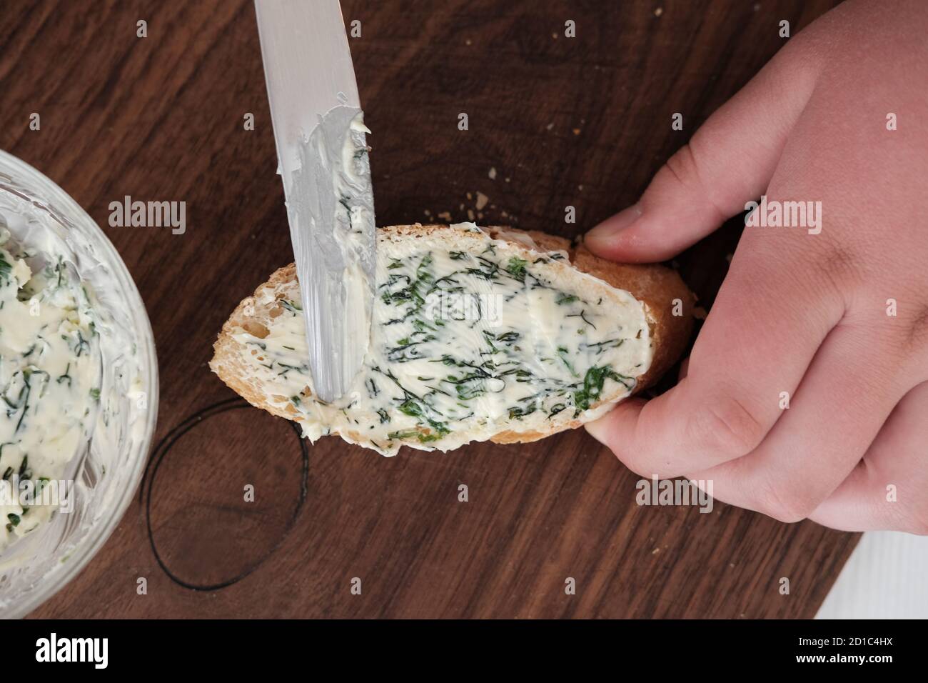 human hands spreading herb butter on a baguette. healthy butter with ...