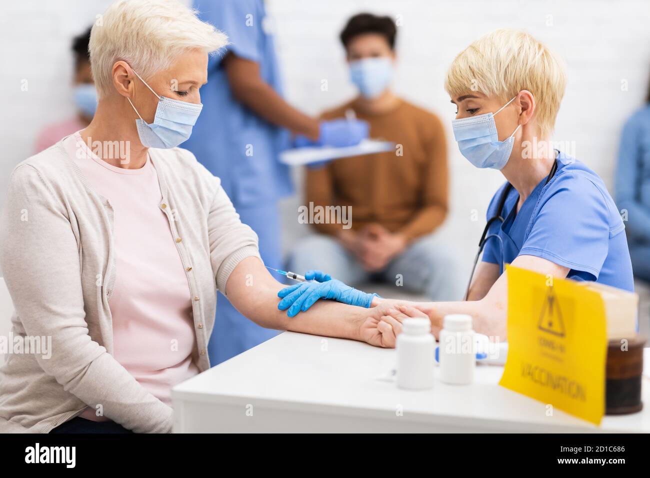 Senior Lady Receiving Covid-19 Vaccine Injection Sitting With Nurse ...
