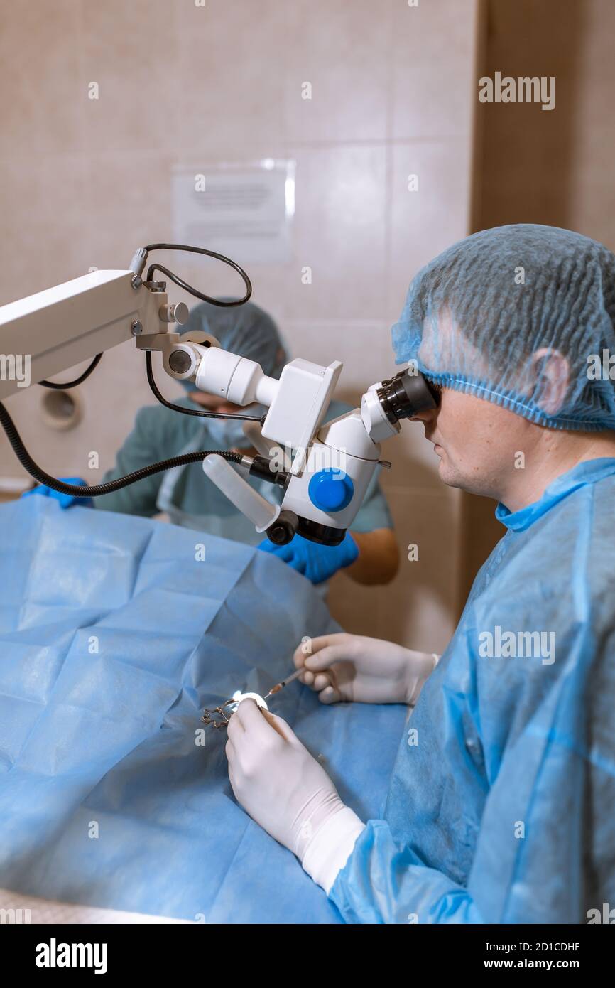 A professional ophthalmologist performs eye surgery with a microscope ...