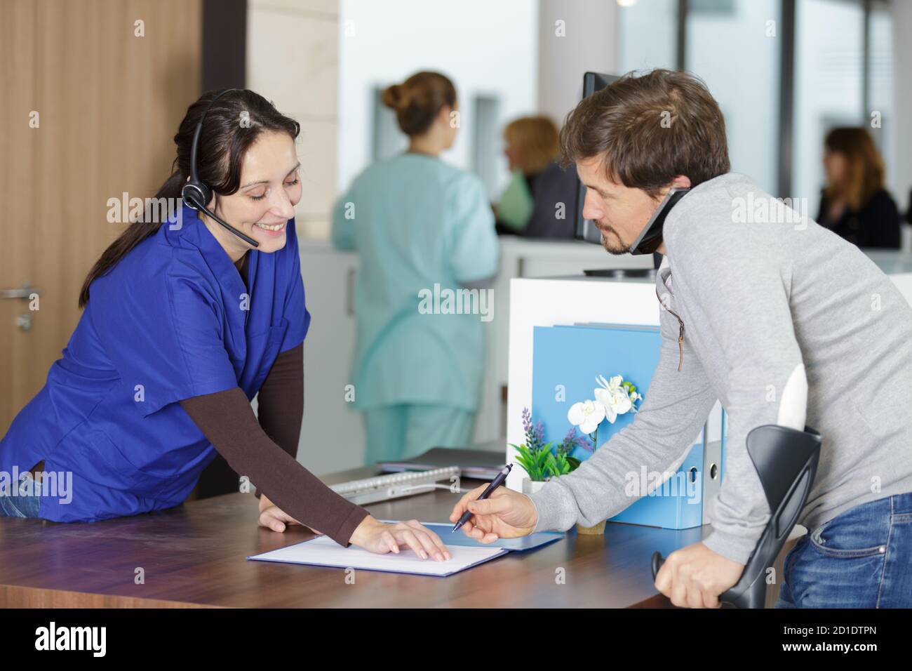 nurse and patient conversing at reception desk in hospital Stock Photo ...