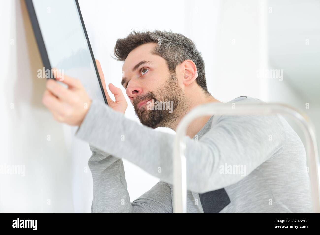 man hanging blank picture frame on wall Stock Photo - Alamy