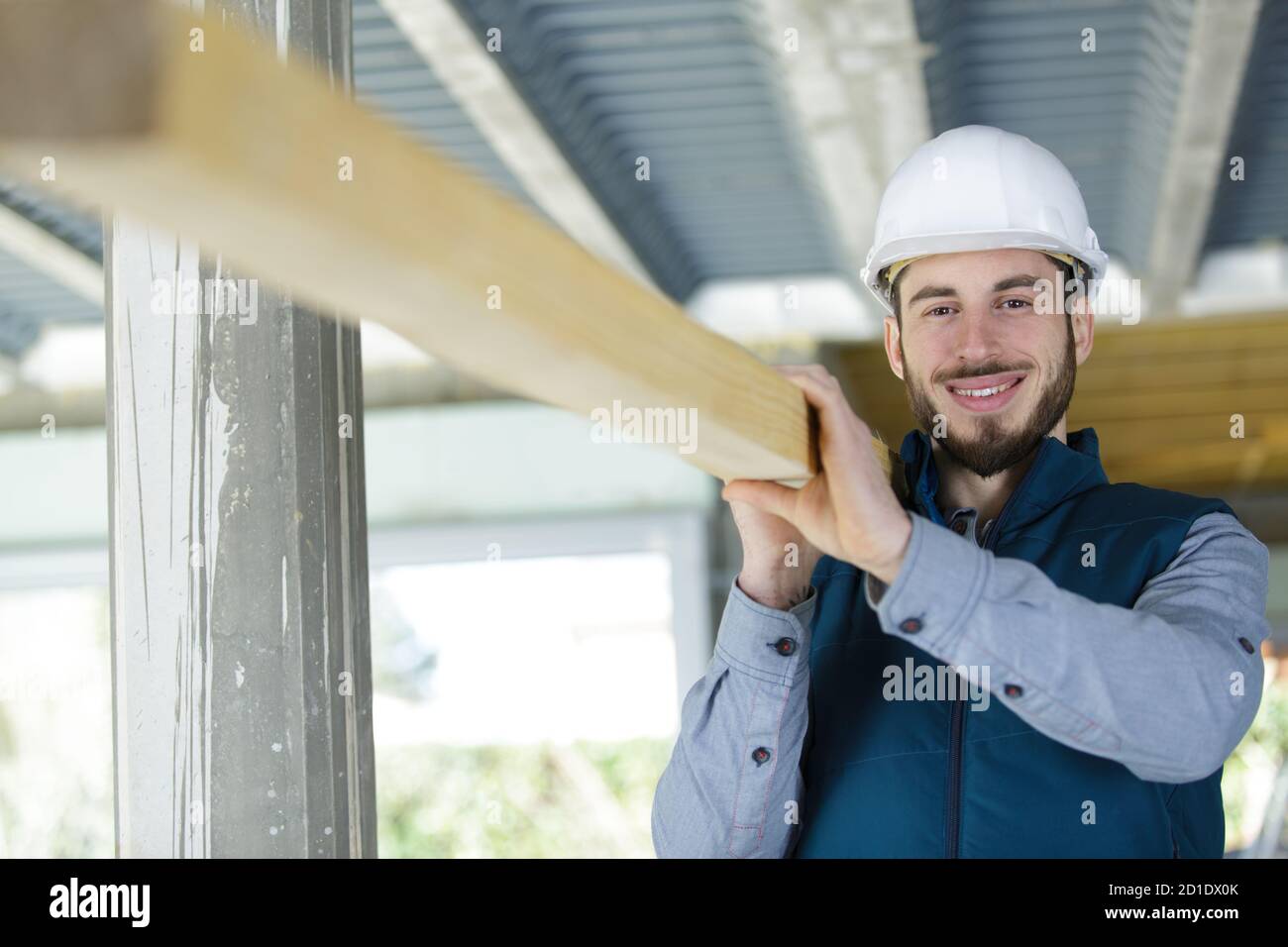 carpenter carrying timber plank at construction site Stock Photo - Alamy