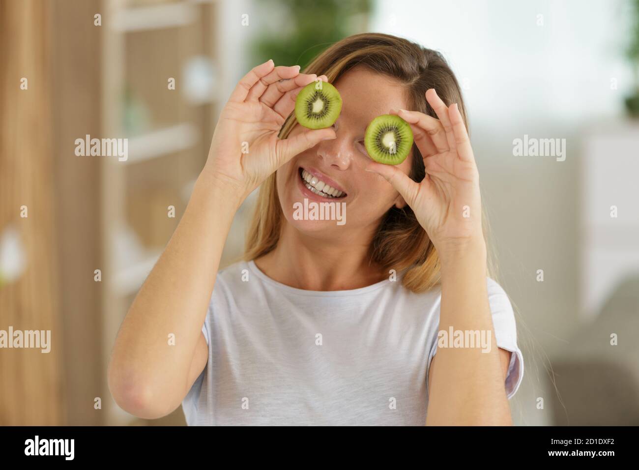 beautiful young woman using kiwis on her face Stock Photo - Alamy