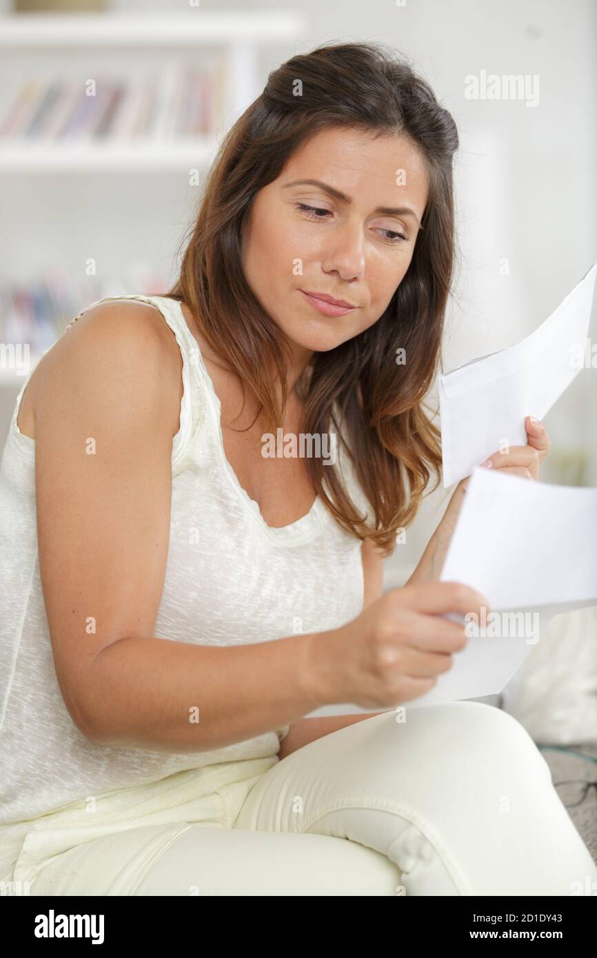 woman sitting on a couch reading a letter Stock Photo - Alamy