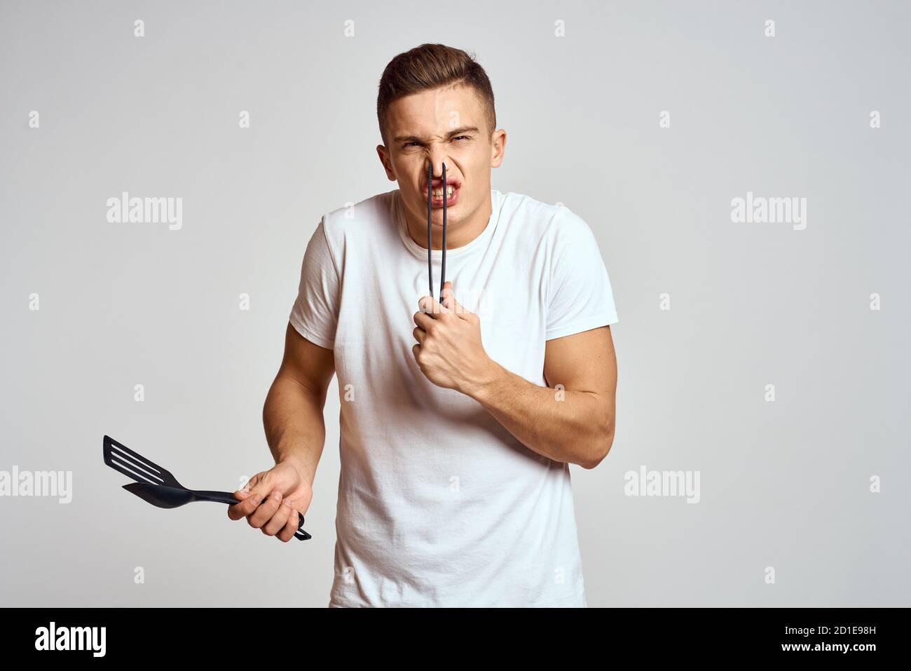 Guy with kitchen tools in hands on a light background cropped view of ...