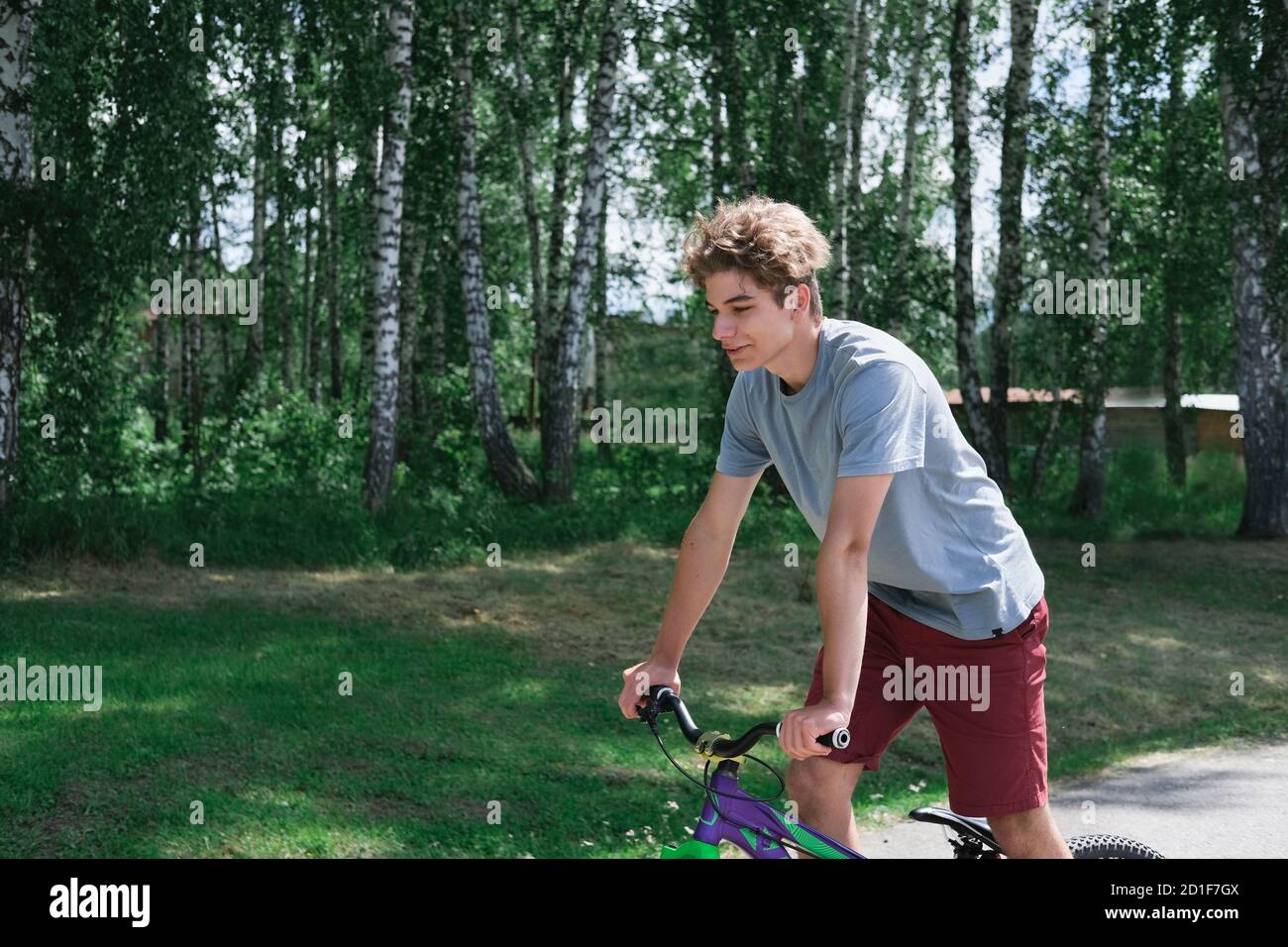 teenager boy riding a bike in a park. curly teenager on a bicycle ...