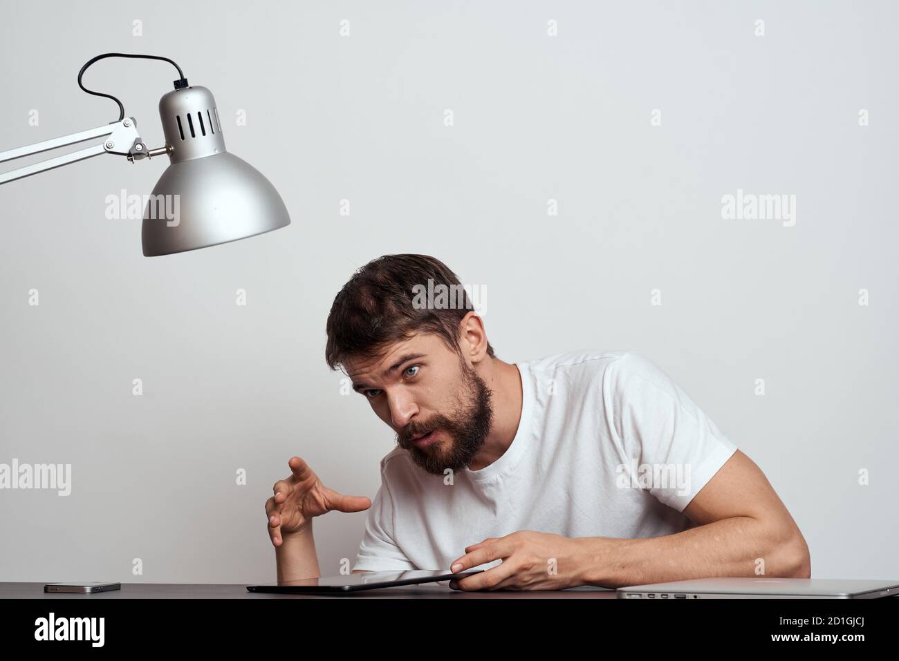 A man with a tablet at the table gestures with his hands on a light ...
