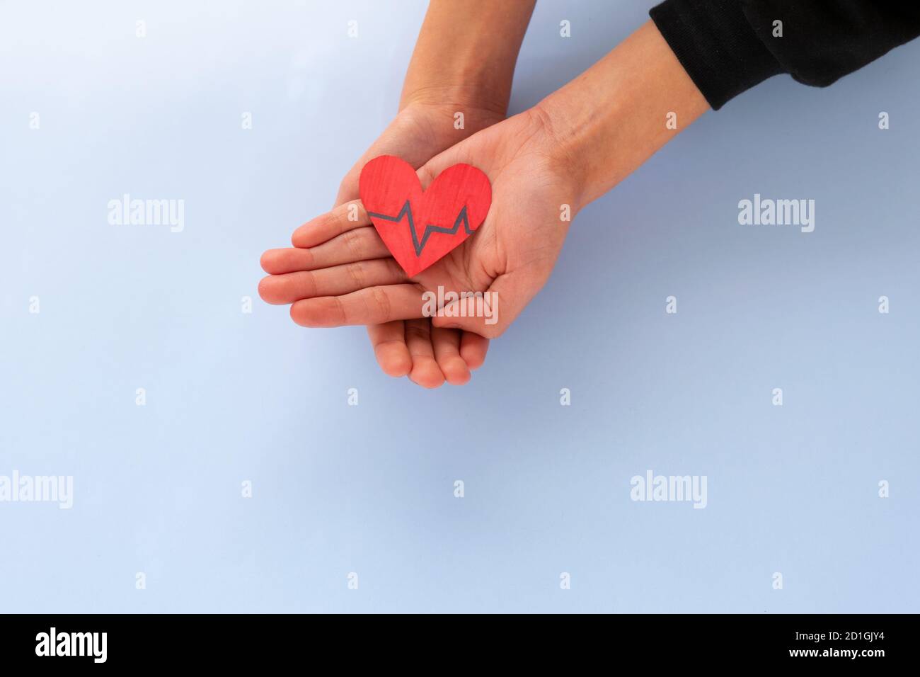 Closeup of hands holding a picture of a heart with a cardiogram ...