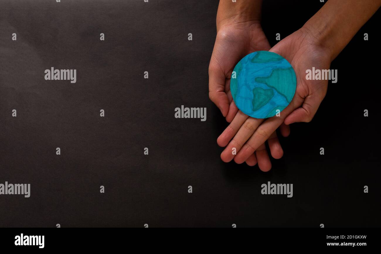 Overhead shot of a paper cutout of the Earth on a person's hand ...