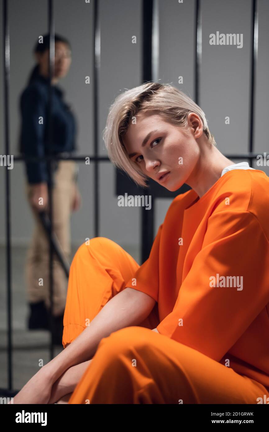 Portrait of a beautiful young criminal in a prison cell against the ...