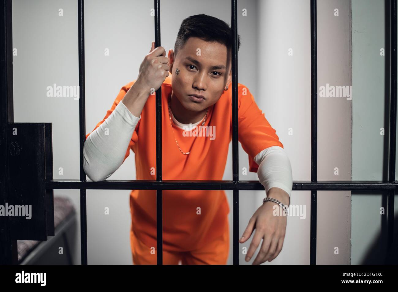 A convicted asian man in an orange robe, with a chain and bracelet and ...