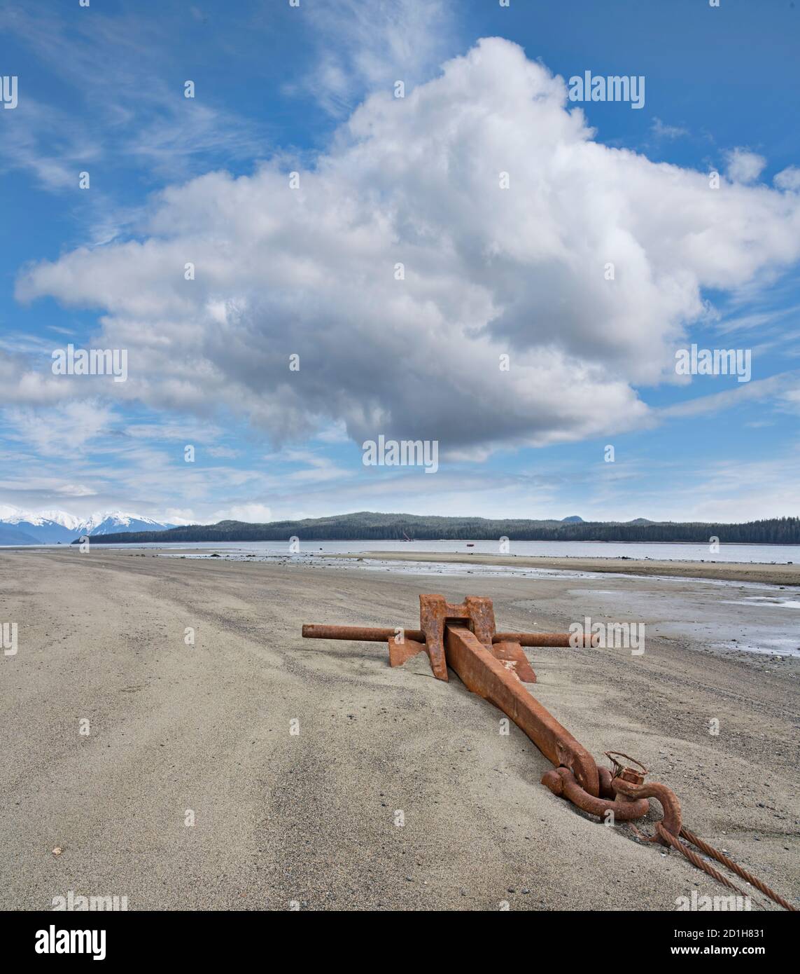 Large rusty anchor on a beach in Southeast Alaska with a puffy cloud ...