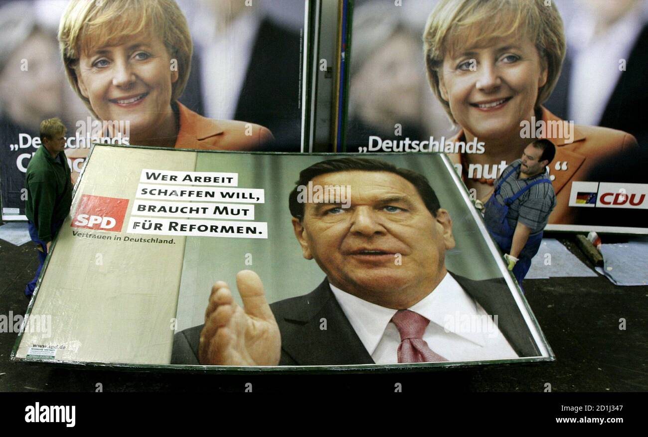 Workers carry an election campaign poster showing German Chancellor ...