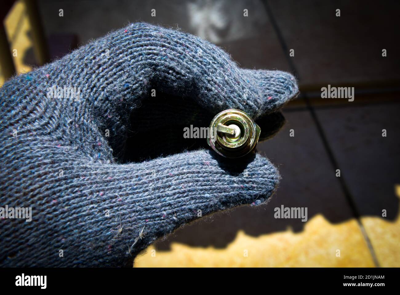 Hand with glove holding spark plug with blurred background Stock Photo ...