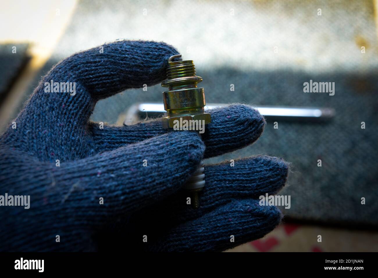 Hand with glove holding spark plug with blurred background Stock Photo ...