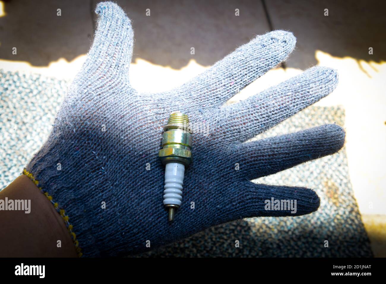 Hand with glove holding spark plug with blurred background Stock Photo ...