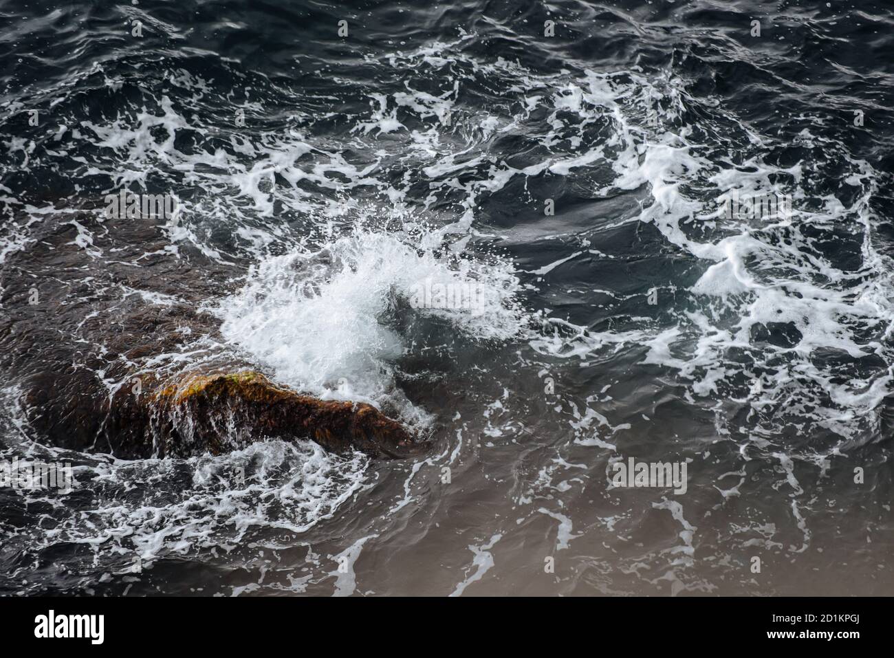 The sea wave breaks against a stone in the water. Splashing water ...