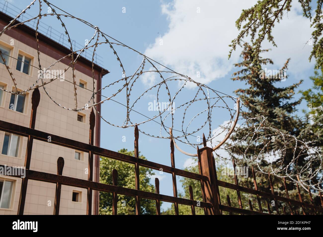 Building wall behind barbed wire barrier with beautiful heavenly clouds ...