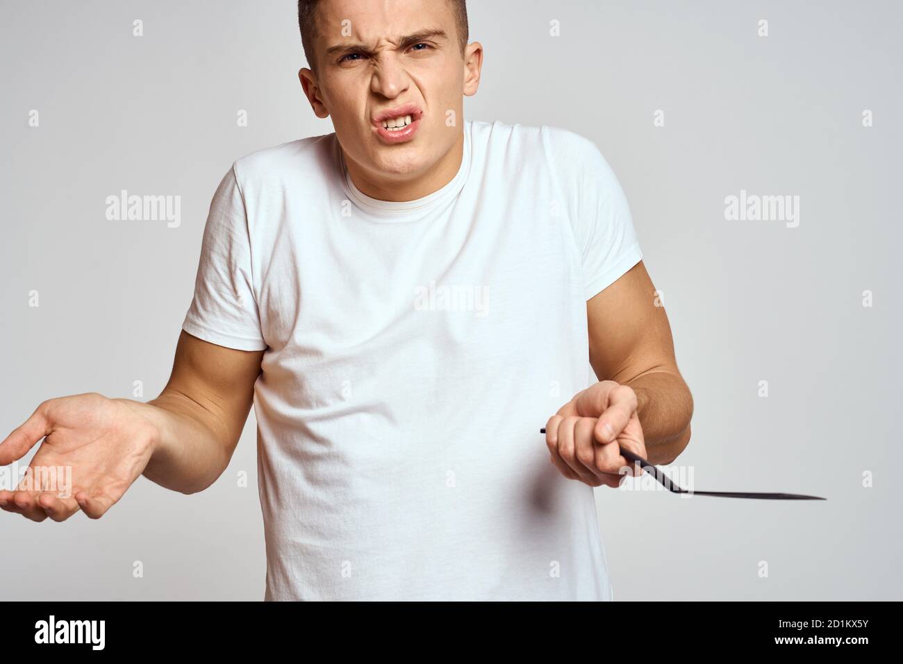 Guy with kitchen tools in hands on a light background cropped view of ...