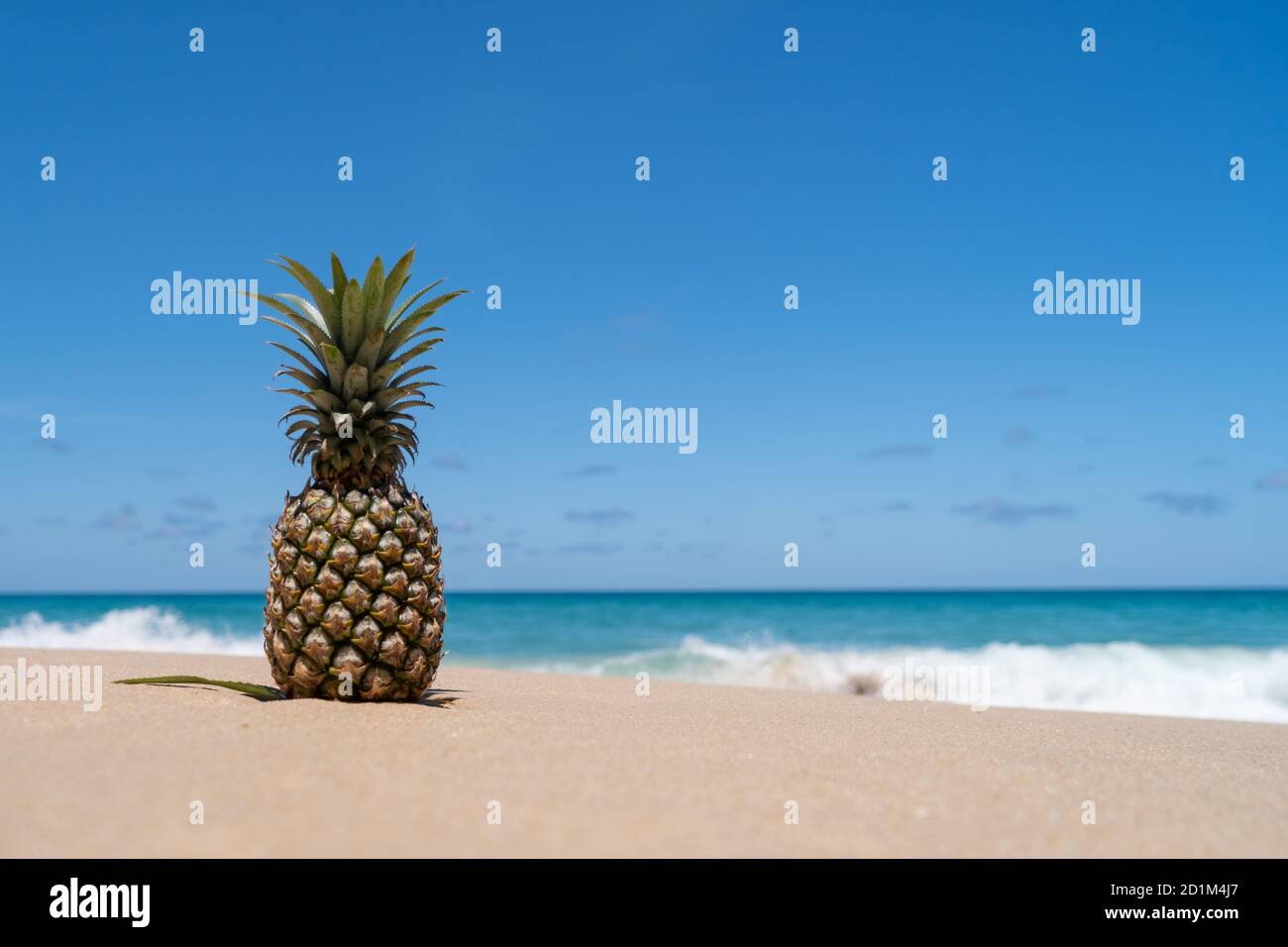 Pineapple on sand with sea water splash on blue sky summer concept ...