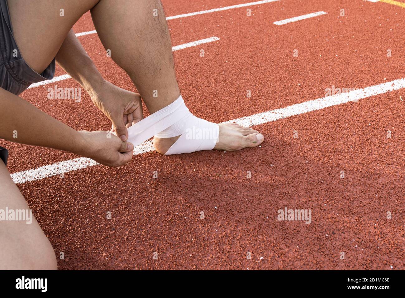 man applying compression bandage onto ankle injury After exercise ...