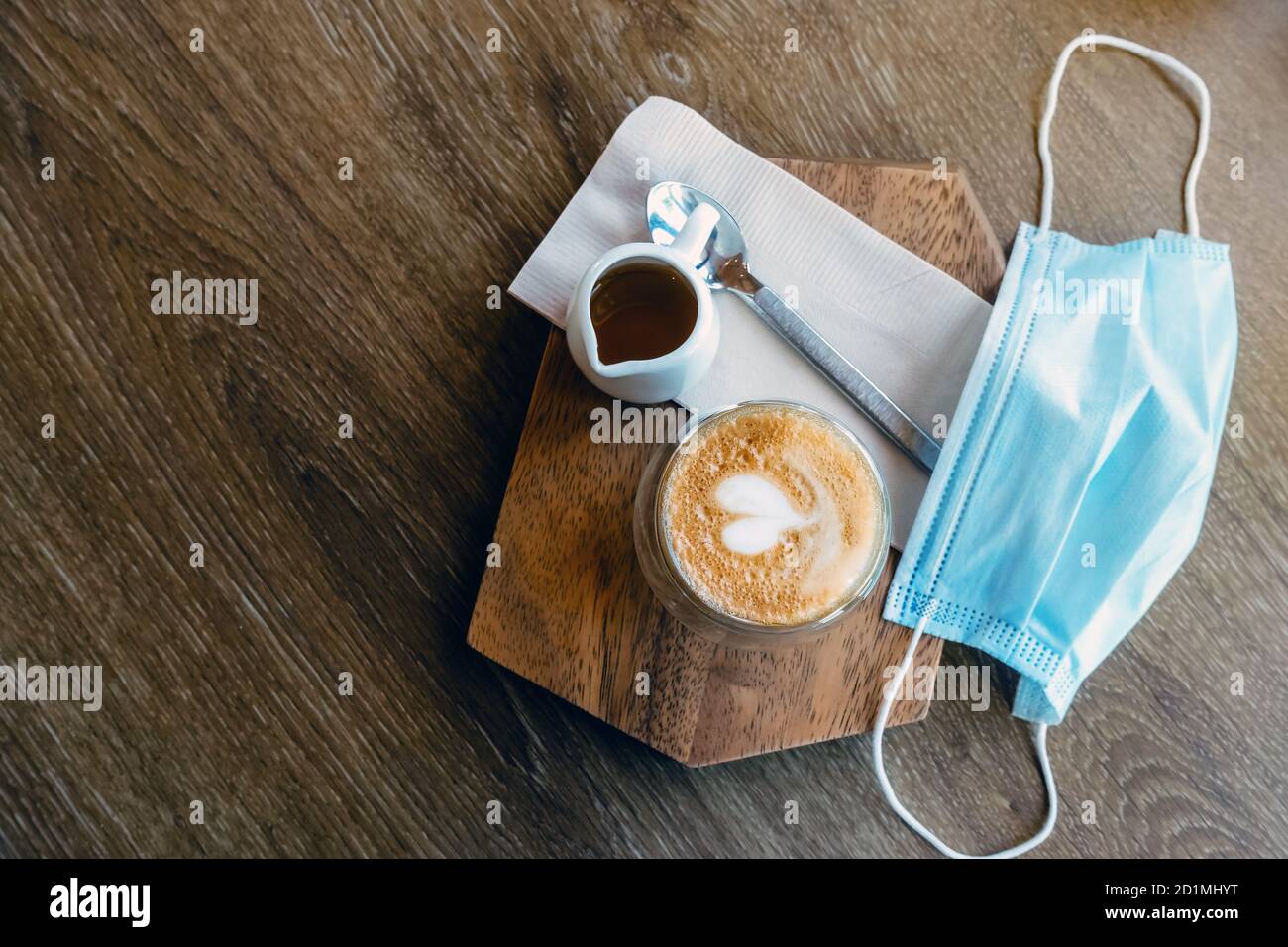 Hot Cappuccino coffee with protective mask on a wooden table for people ...
