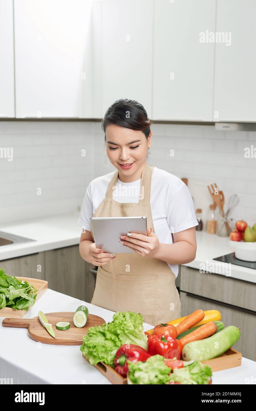 Beautiful housewife lady hold digital tablet searching recipe internet ...