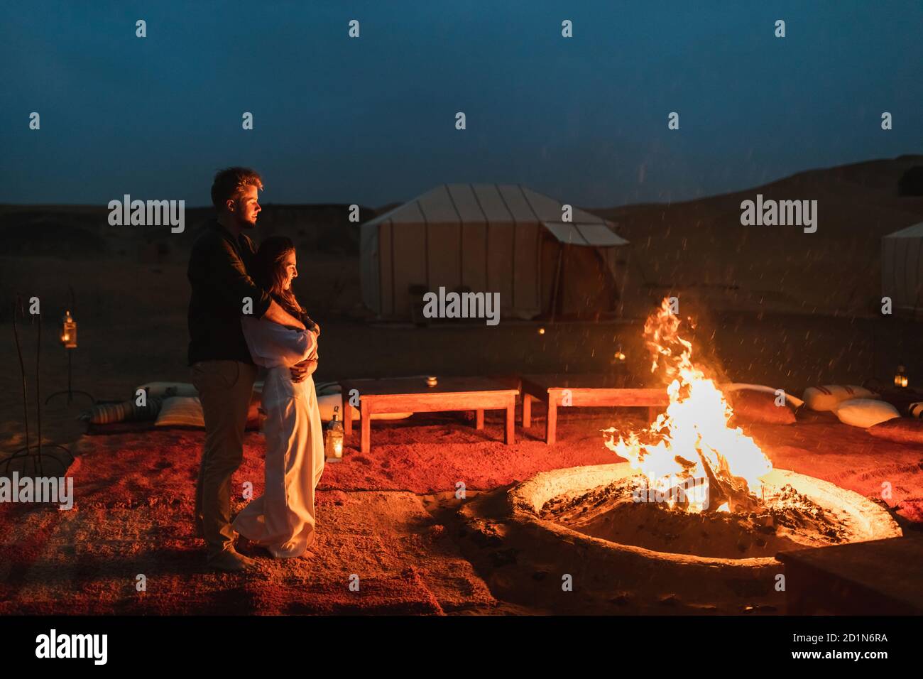 Couple hug in love near big campfire. Romantic night in glamping desert camp in Sahara, Morocco ...