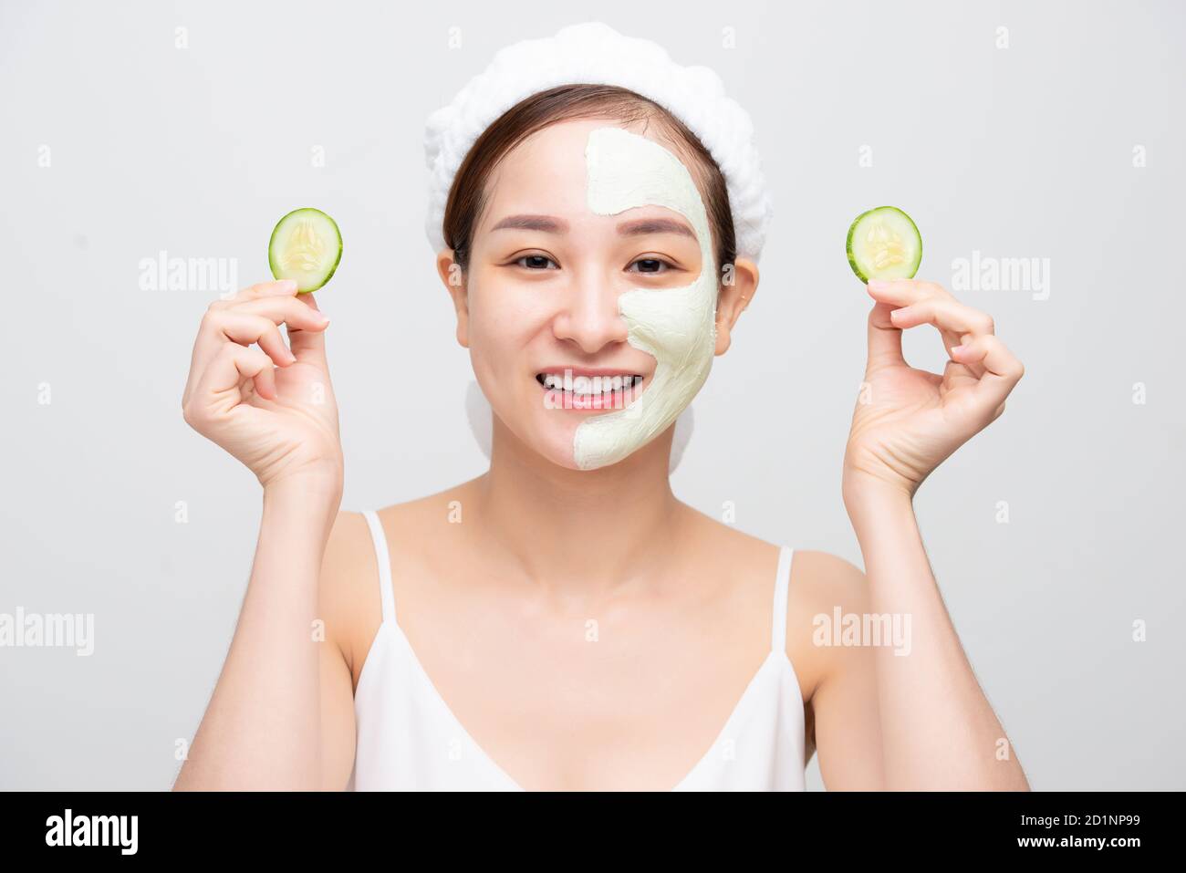 Attractive young Asian woman with clay mask and holding fruit piece ...