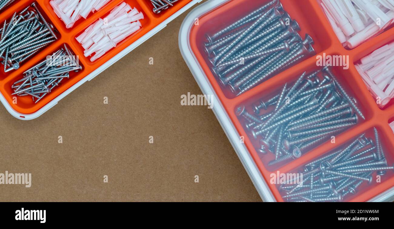 Steel silver screws and wall plug in orange plastic box. Top view tool ...