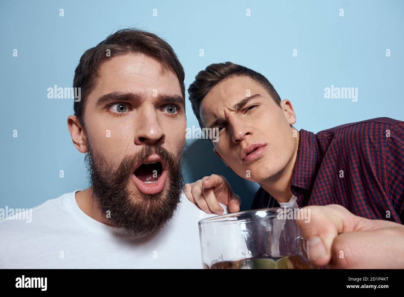 Two cheerful drunk friends drinking beer lifestyle emotions on a blue ...