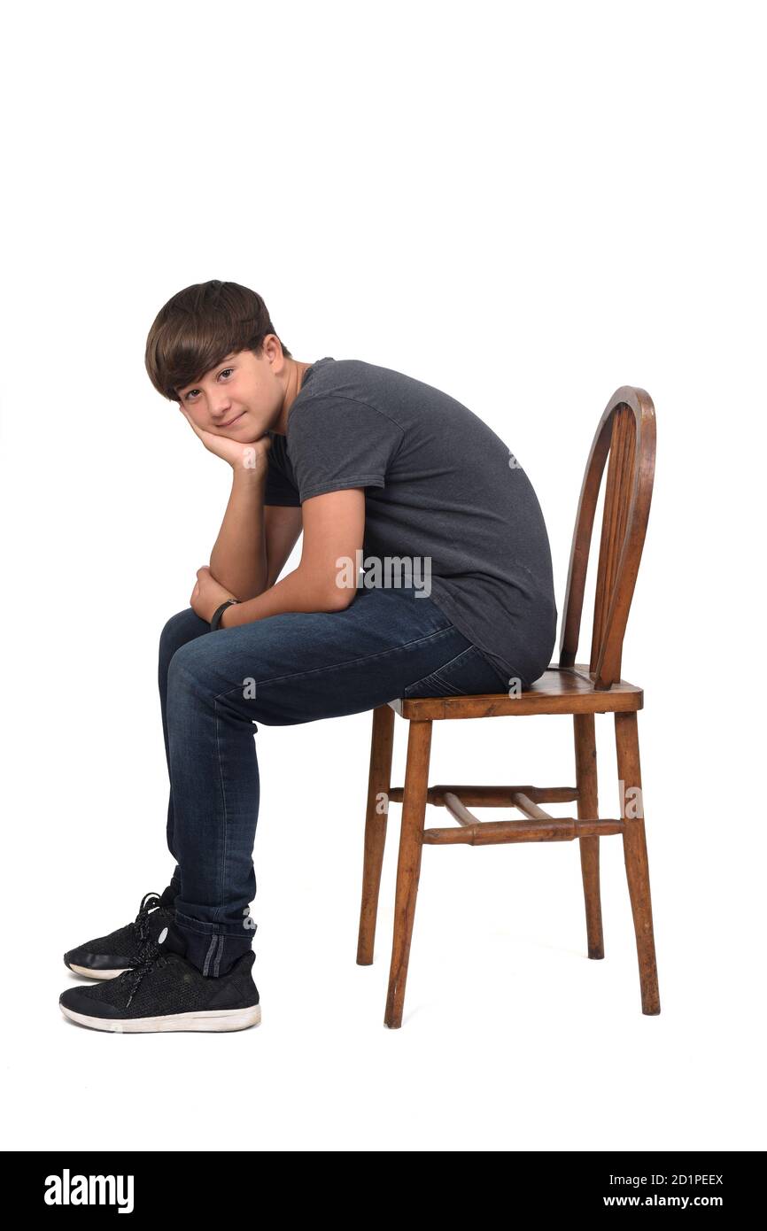teenage boy sitting and crouching on a chair with white background ...