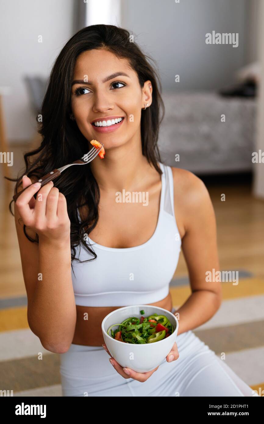 Fit woman eating healthy salad after working out at home Stock Photo ...