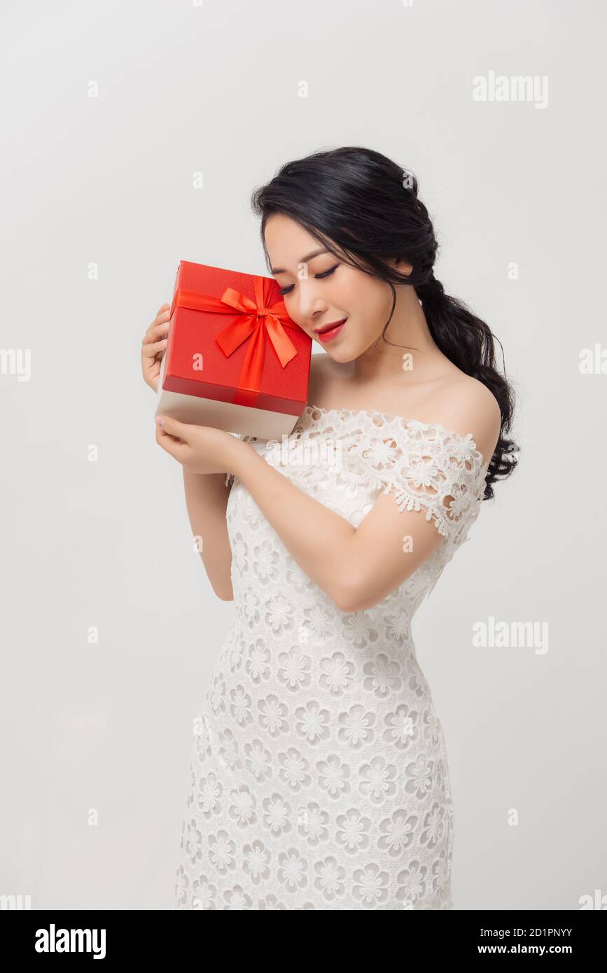 Happy young elegant Asian woman holding special gift box and wearing ...