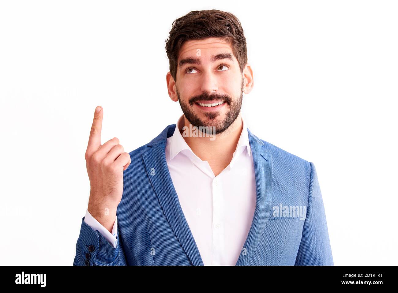 Studio shot of smiling young man in suit pointing upwards with his ...