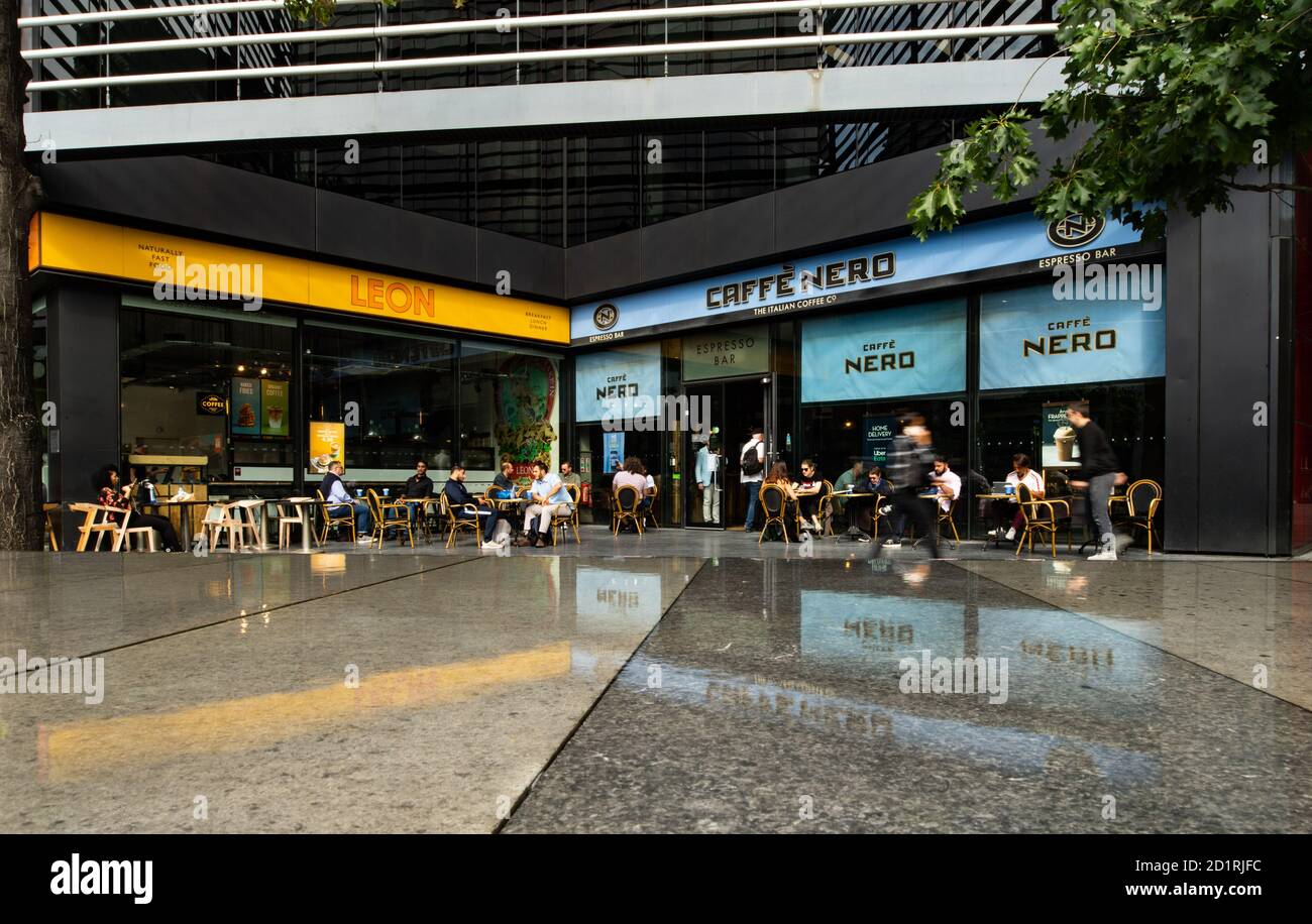 People sit outside a Caffe Nero and Leon food retail chain cafe in ...