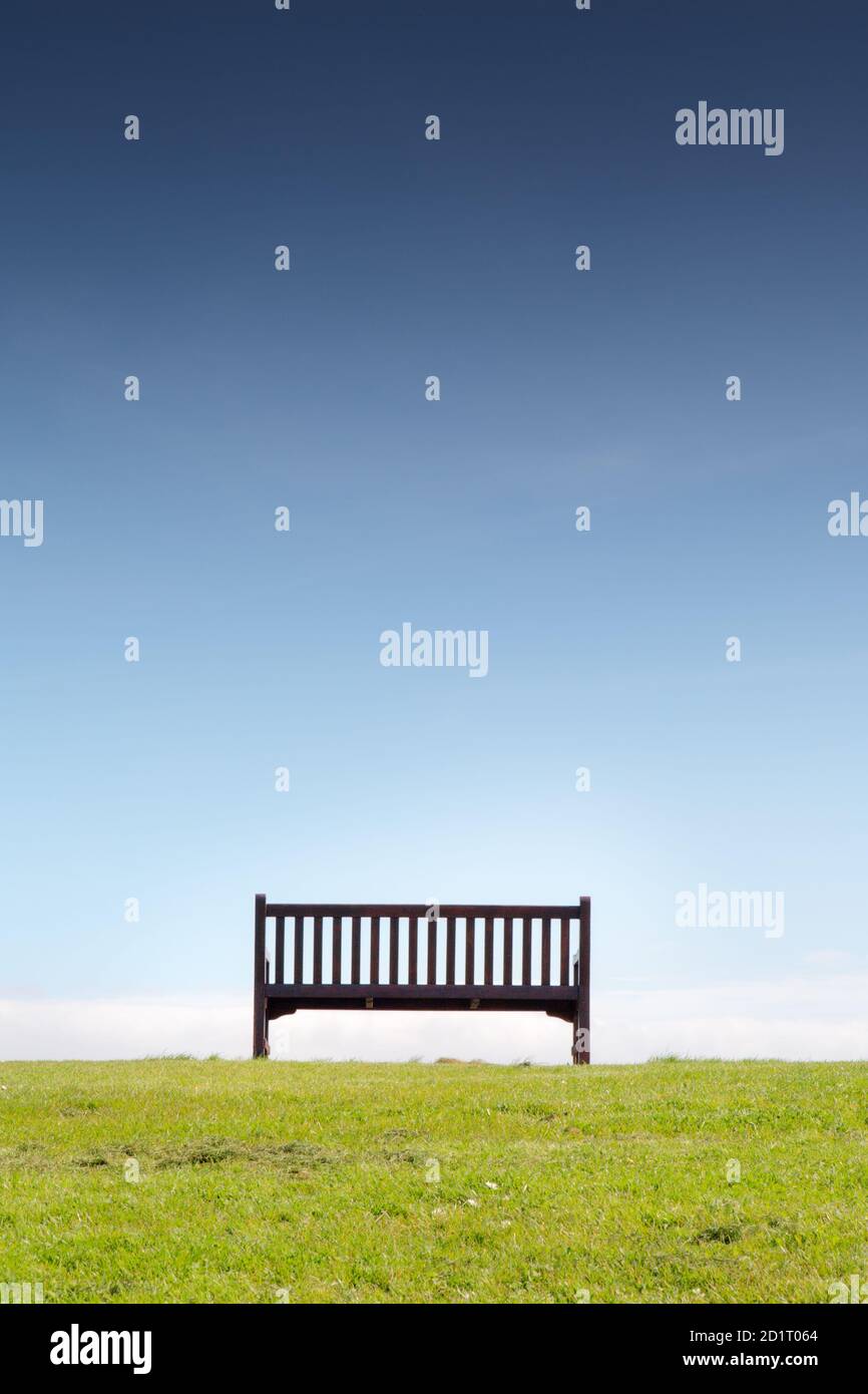 single bench on grass against a blue sky Stock Photo - Alamy