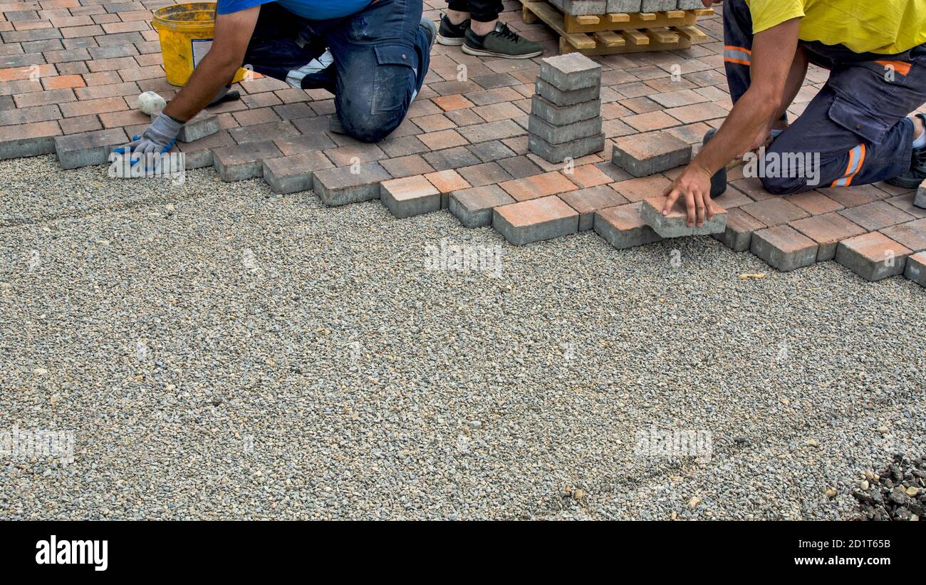 Master lay and install floor bricks on a public surface. The base is ...