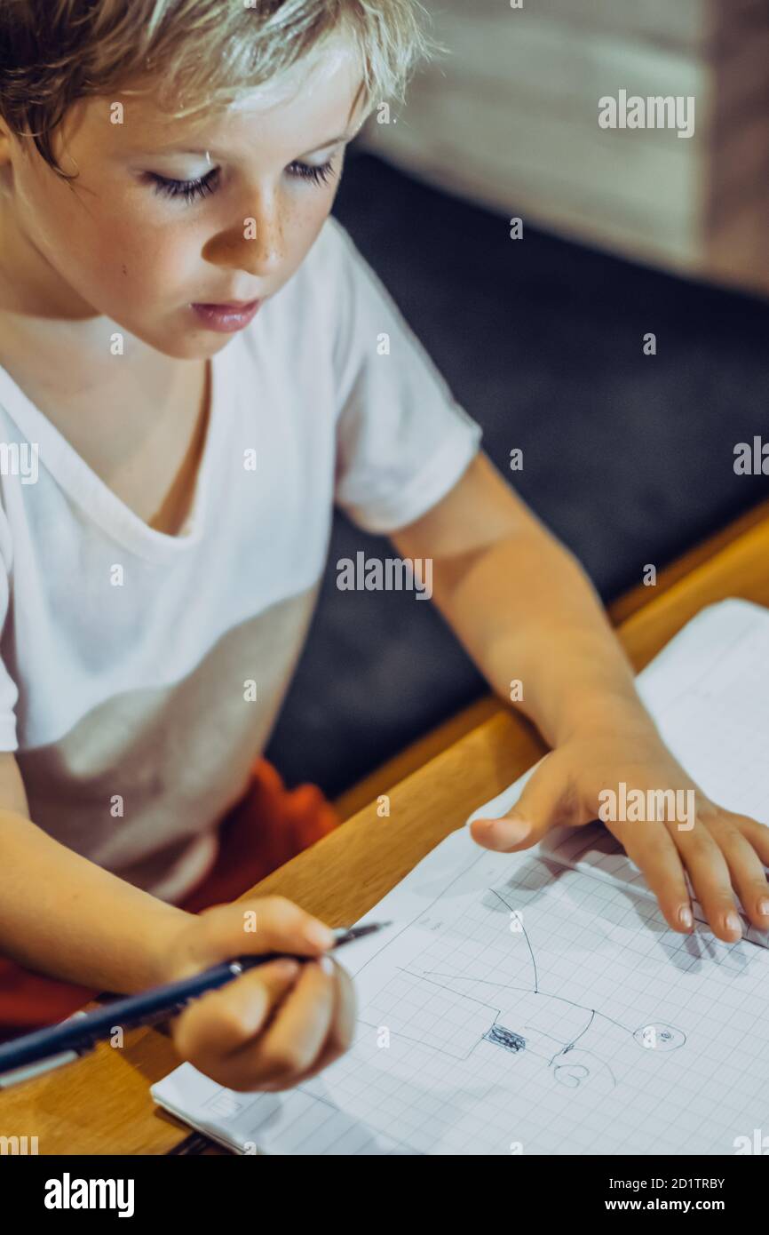 Portrait blond Preschool boy holding pen notebook look serious hard ...