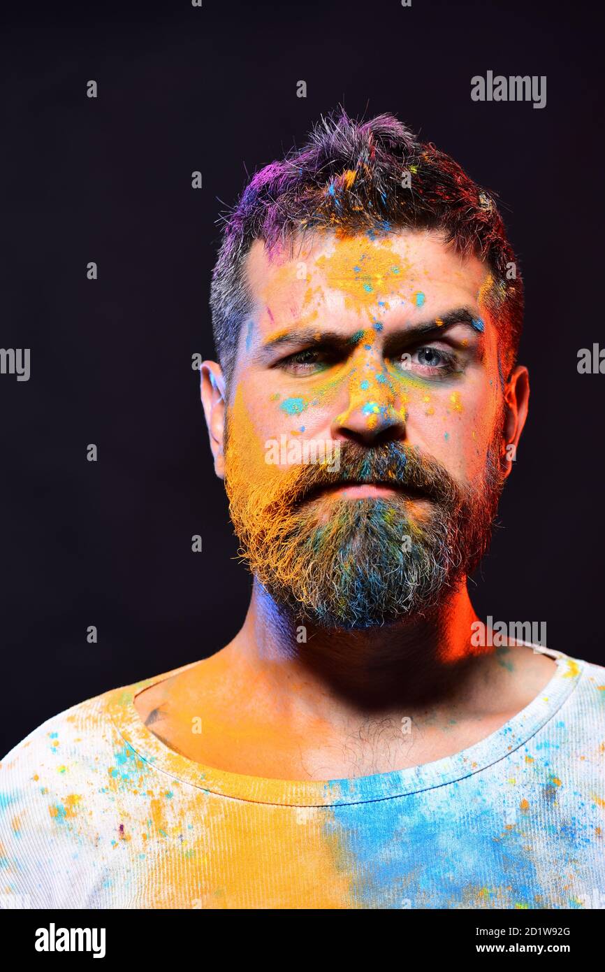 Color and holiday concept. Man with beard have paint spots on face. Guy ...