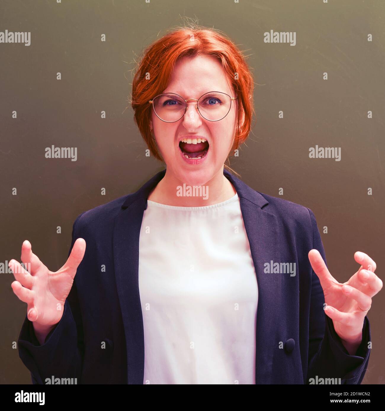 A female teacher with a face red with rage. Angry teacher yells at the ...