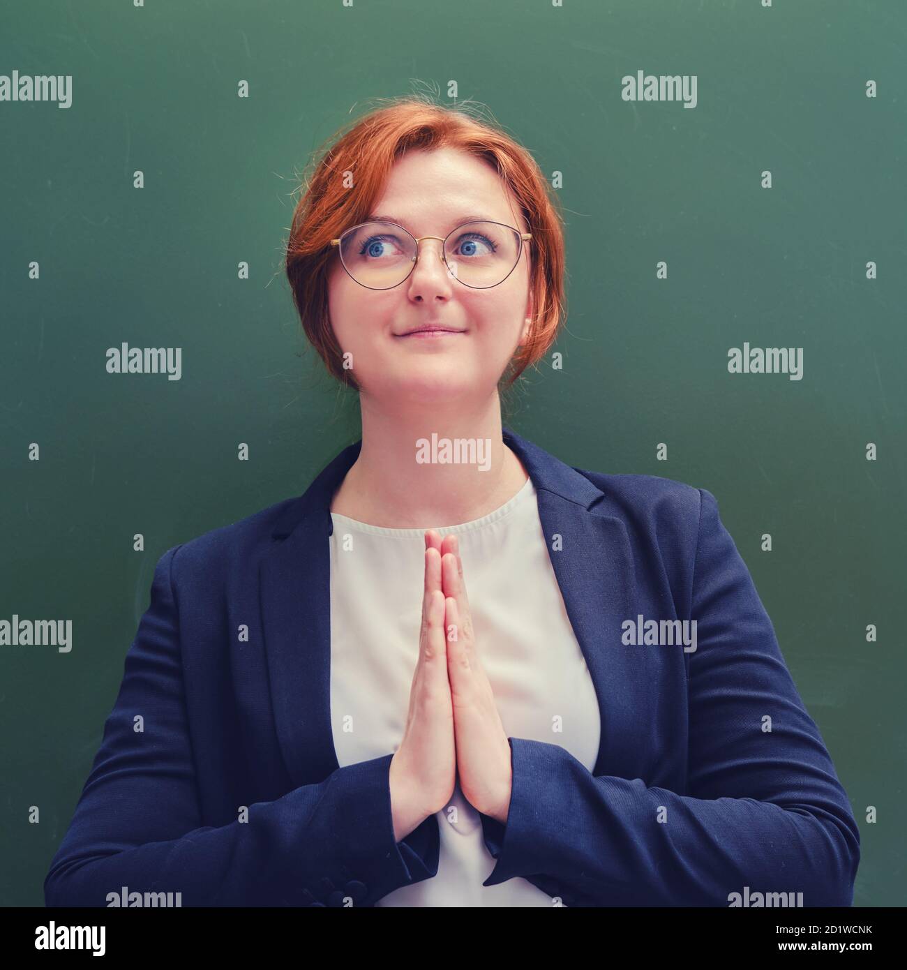 Female teacher stands with a beatific face and hands clasped in prayer ...