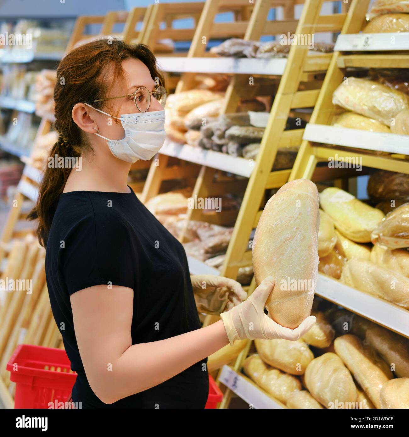 Adult woman in medical mask buys a loaf of bread in a supermarket Stock ...