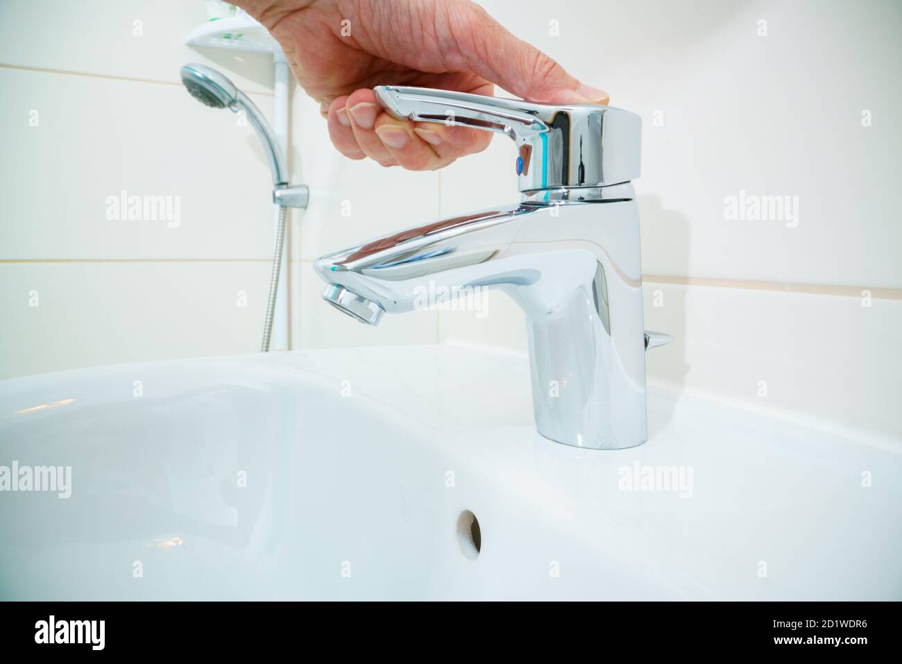 Man is closing water flow tap with water. Water running from chrome ...