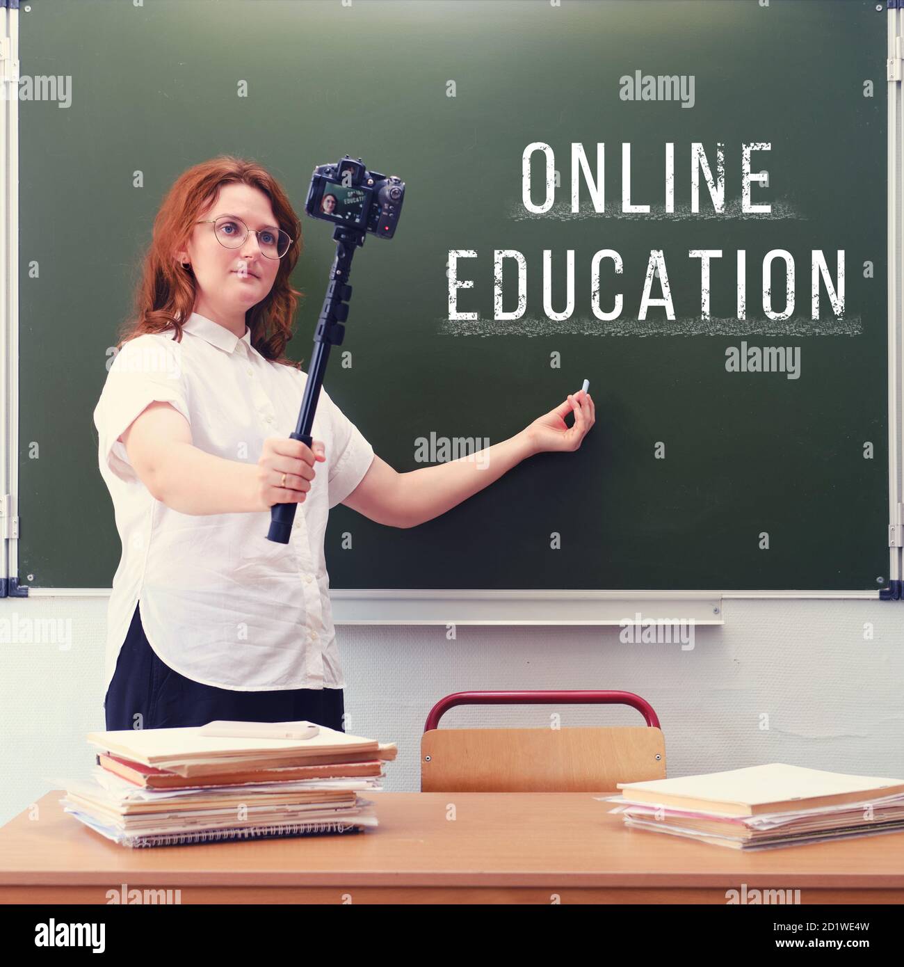 The teacher stands with a video camera at the blackboard and films ...