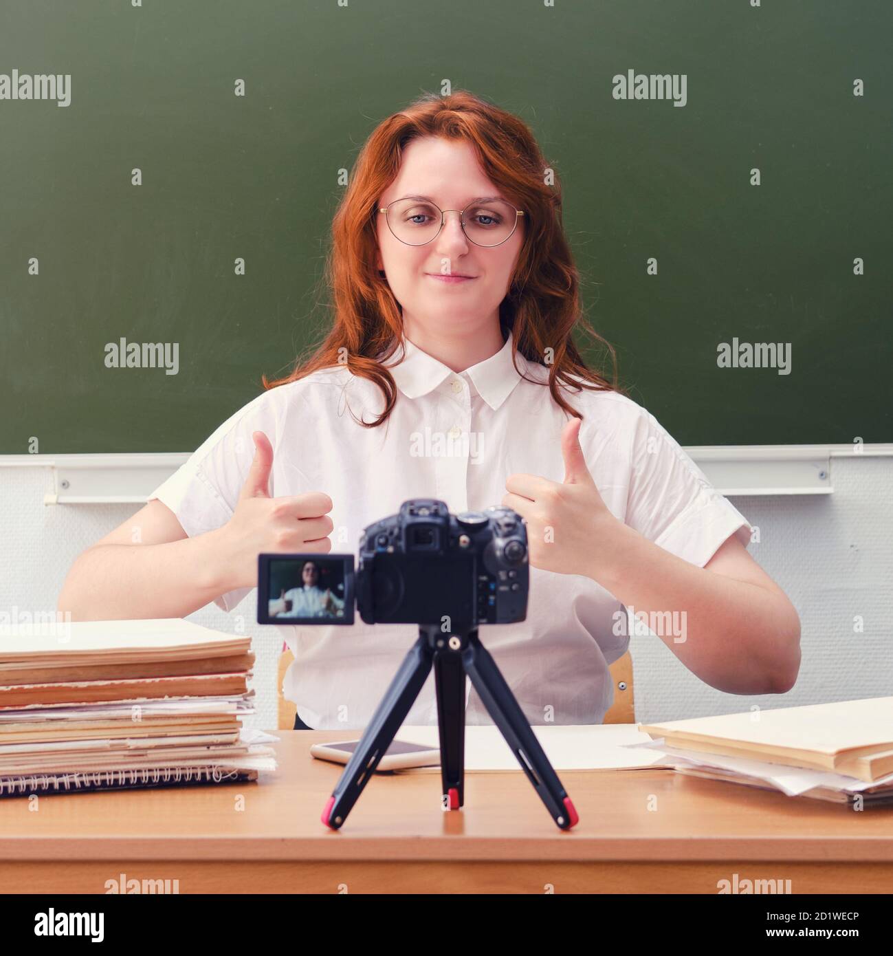 Smiling teacher showing thumbs up gesture to the camera during online ...