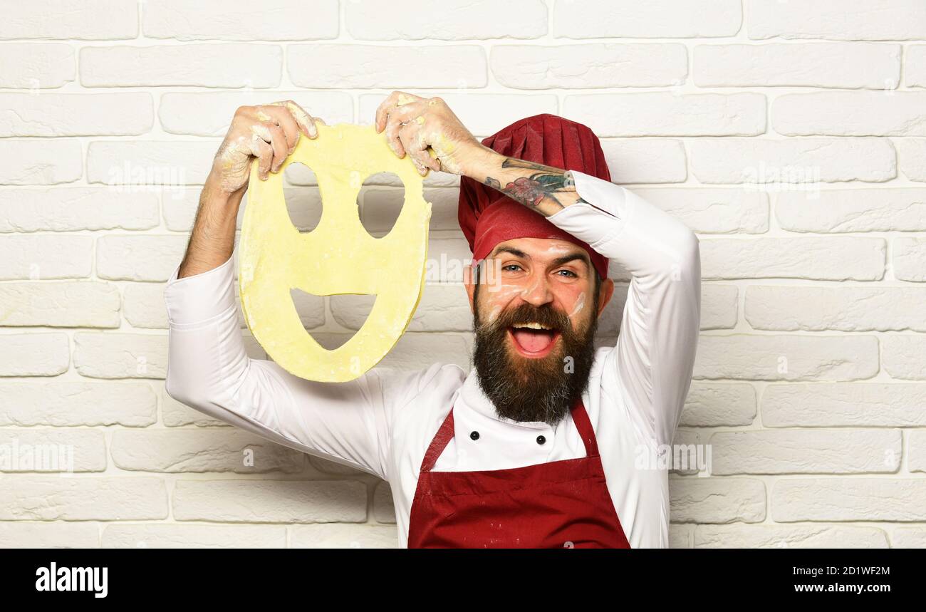Cook with excited face in burgundy uniform plays with pizza dough ...