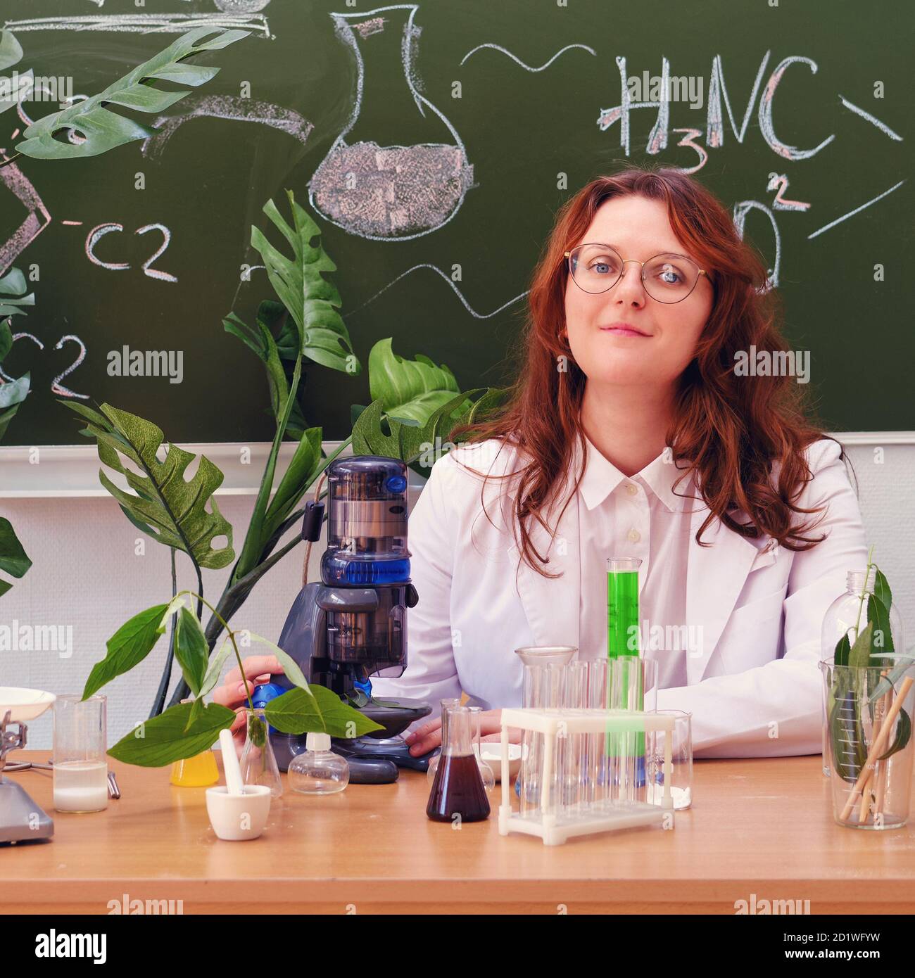 Cute woman teacher with microscope in school class at chemistry lesson ...